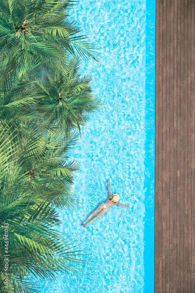 Young alone active woman in bikini and hat is swimming in swimming pool ...
