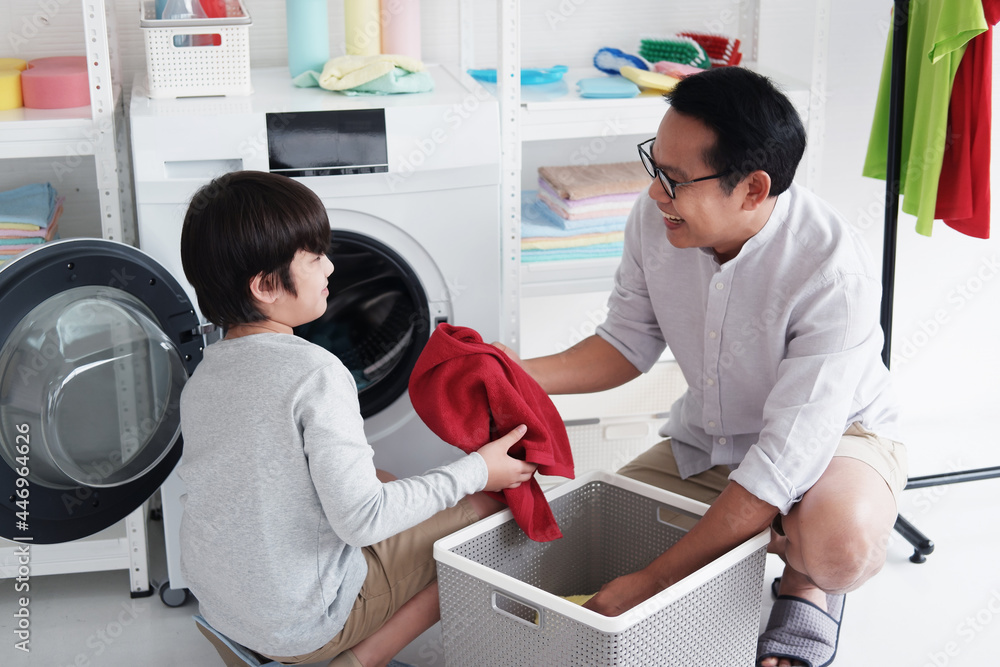 Smiling Asian father and little boy child are putting the clothes in ...