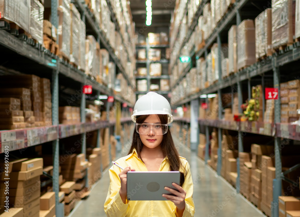 Female warehouse worker inspecting a warehouse in a factory. Wear a ...