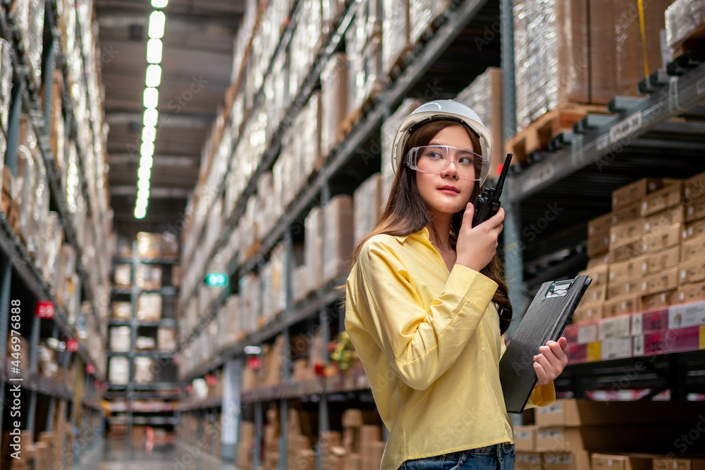 Female warehouse worker inspecting a warehouse in a factory. Wear a ...