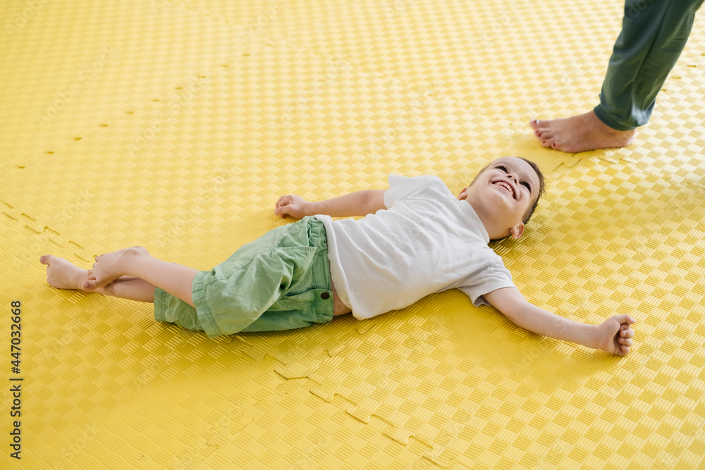Happy child on the mat in child rehabilitation center. Boy with ...