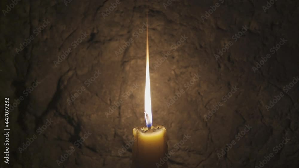 yellow candle in dark cave calm with burning candle flame on night ...
