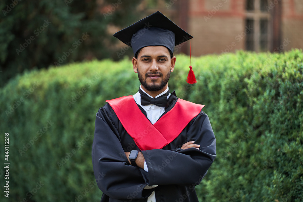 Portrait of indian handsome male graduate in graduation robe with ...