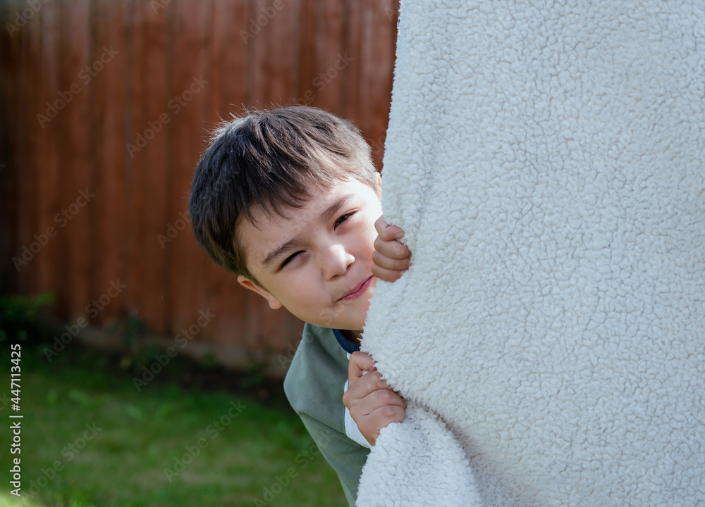 Happy kid playing hide and seek in the garden, Cute boy looking at ...