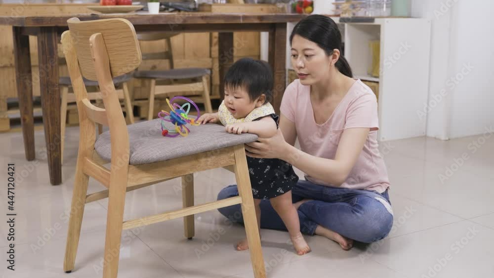 asian parent seated on the floor at home is clapping hands happily ...