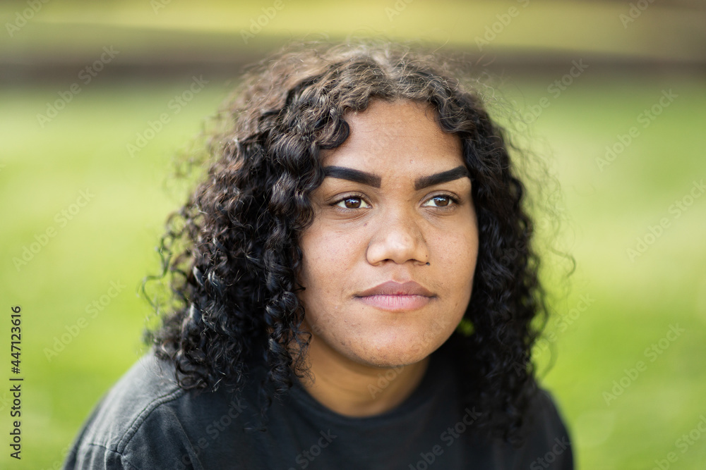 head and shoulders of indigenous girl with curly hair and blurry ...