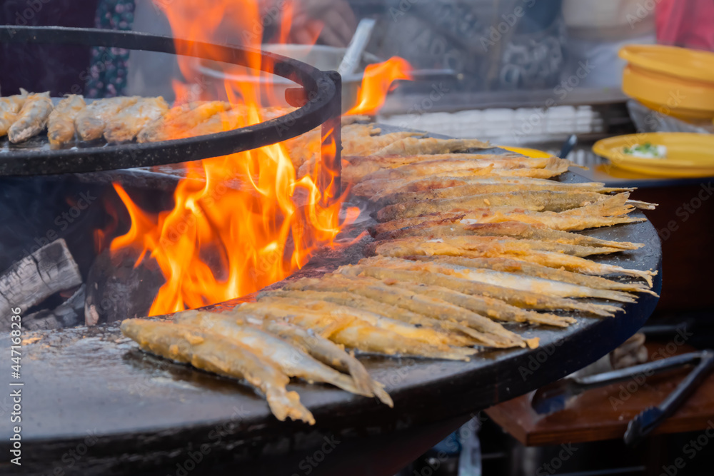 Process of cooking european smelt fish in flour on black brazier with ...