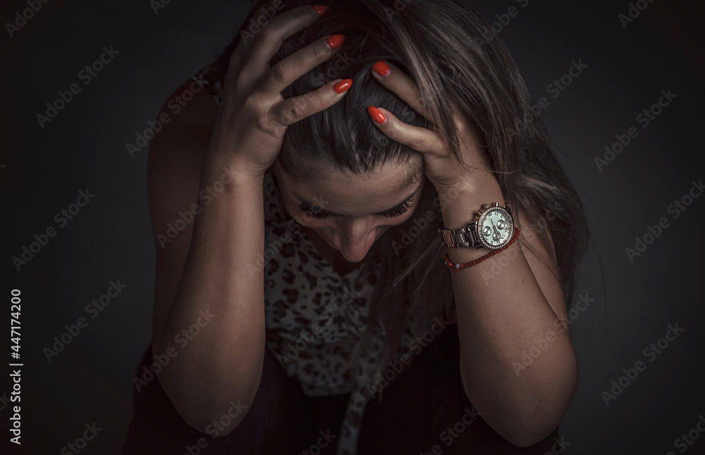 Young, desperate girl sitting and holding her head in agony Stock Photo ...