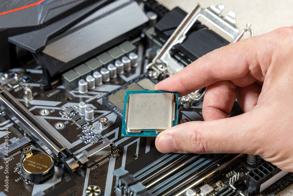 Installing the CPU into a socket on the motherboard. The technician holds the blank central ...