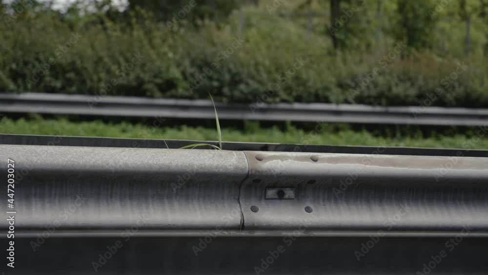 Cars passing in slow motion on a high way, with nature reaching out ...