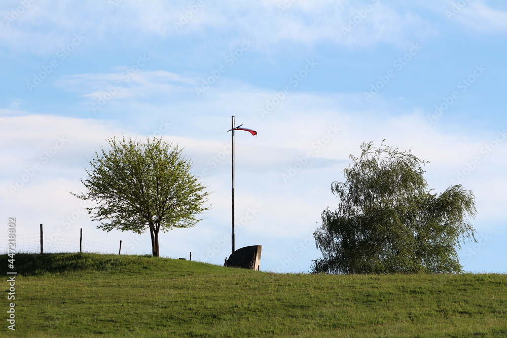 Rusted tall metal flag pole with dilapidated broken flag on top waving ...