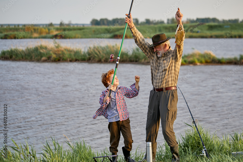 Optimistic caucasian senior fisherman and child boy enjoy fishing ...