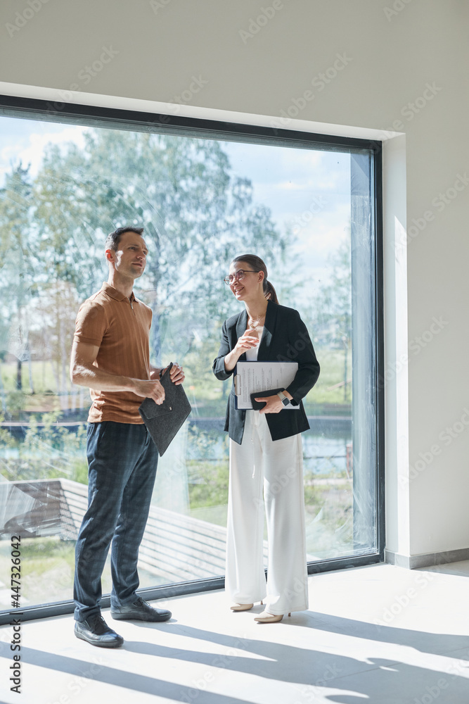 Full length portrait of female real estate agent giving apartment tour ...