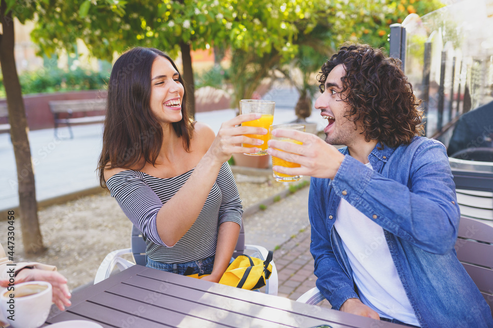 Couple of friends toasting while having a drink with their multi-ethnic ...