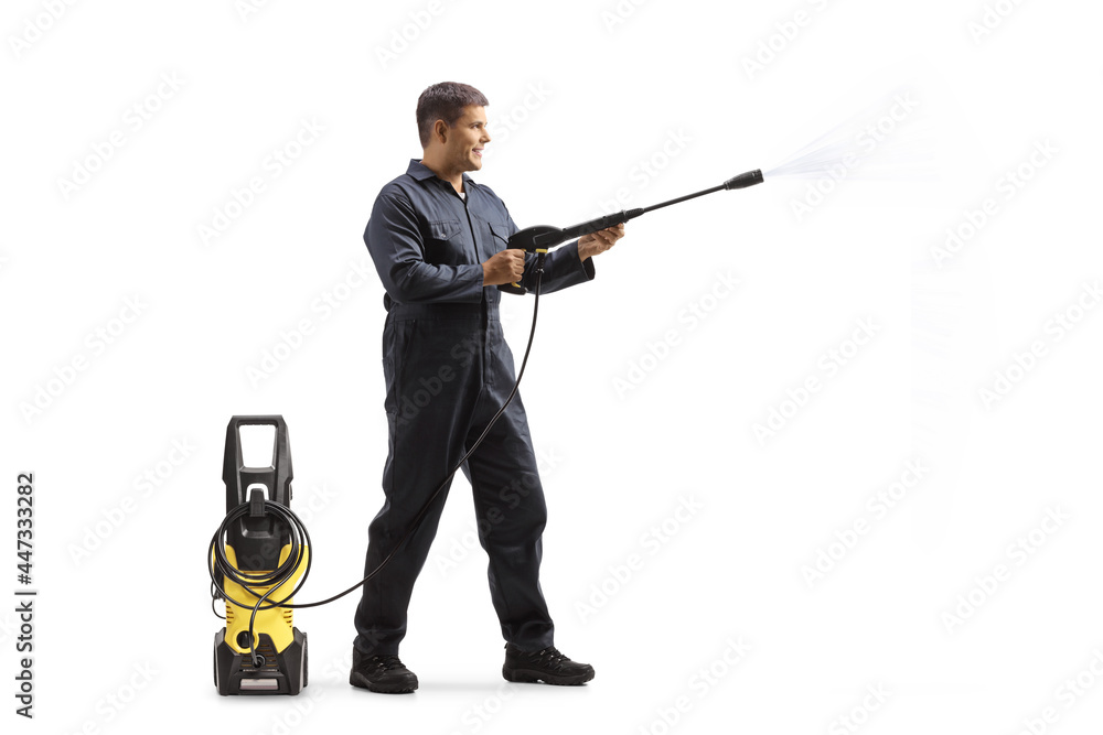 Full length profile shot of a male worker in a uniform using a pressure ...