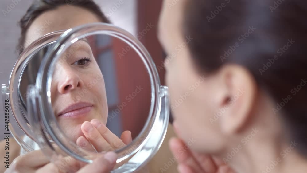 Vídeo do Stock: Look at facial wrinkles in the mirror. A worried woman ...
