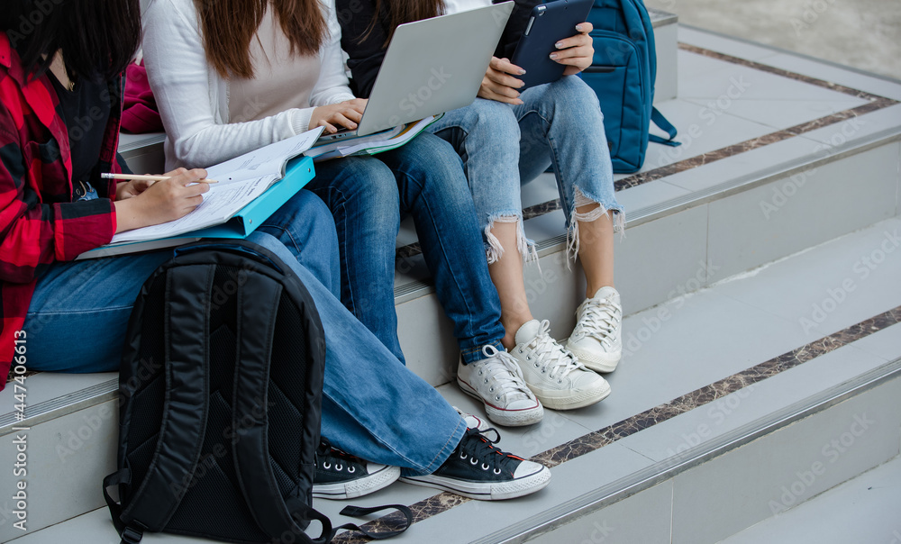 Group of three young girls college students legs and sneakers sitting ...