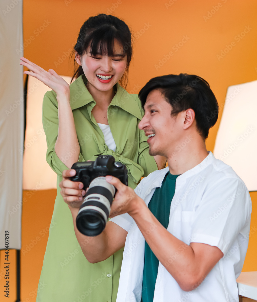 A happy professional male photographer holding a DSLR camera laughing ...