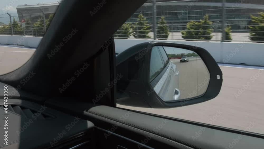 Black car in motion, the road is reflected in the side view mirror ...