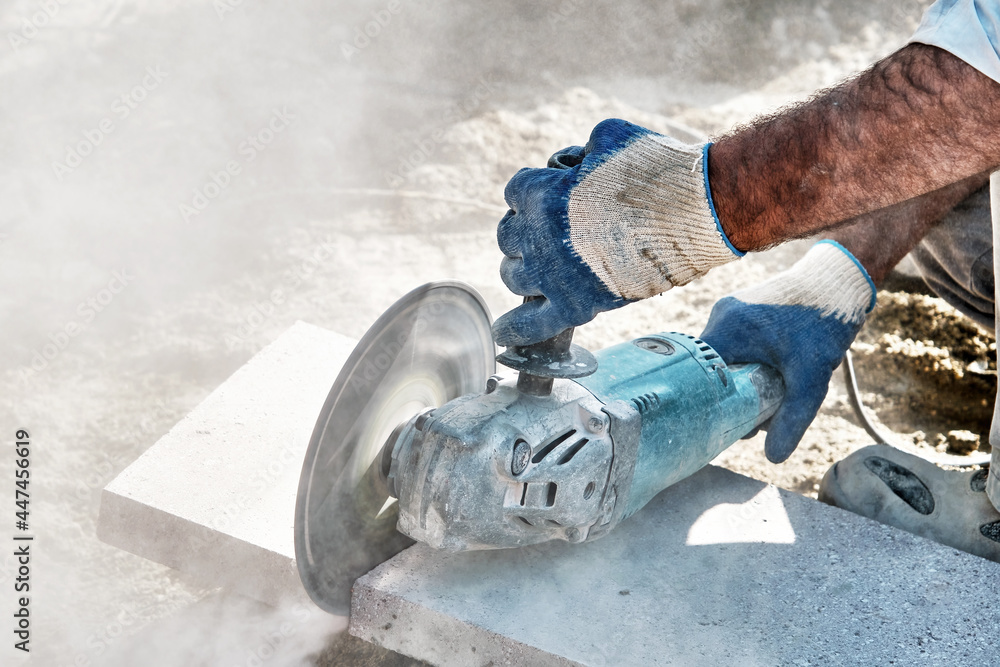 Hands of a pavement construction worker using an angle grinder for ...