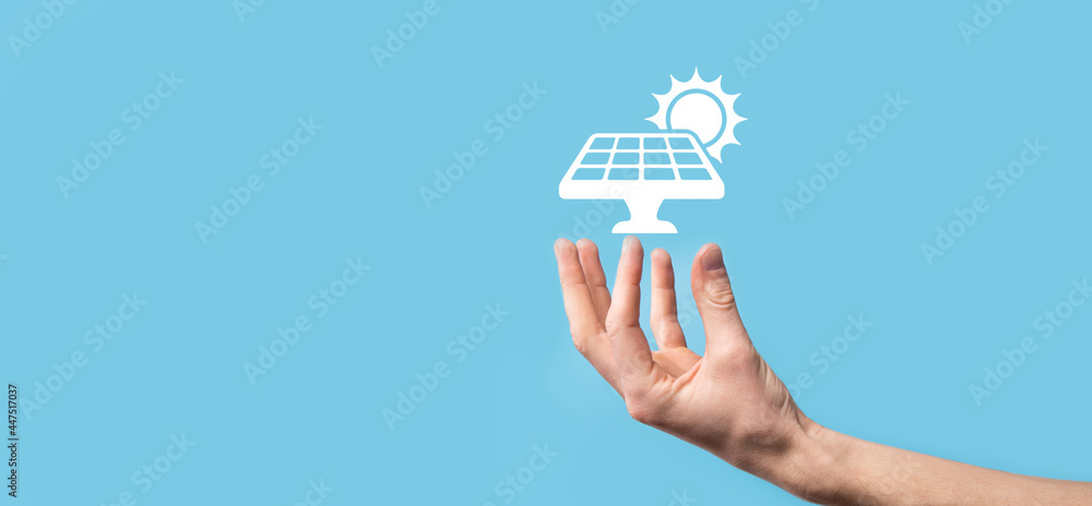 Hand on a blue background holds the icon symbol of solar panels ...