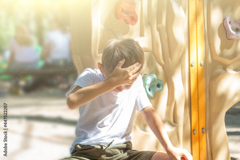 Upset cute child boy sitting after falling. Little climbing wall on ...
