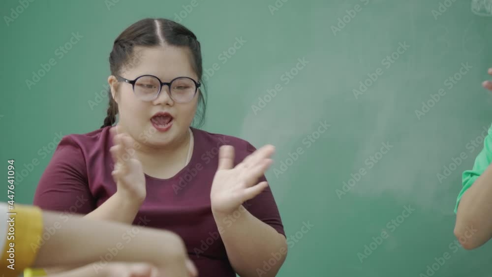 Autistic Asian girl sit in classroom with teacher and friend to do ...