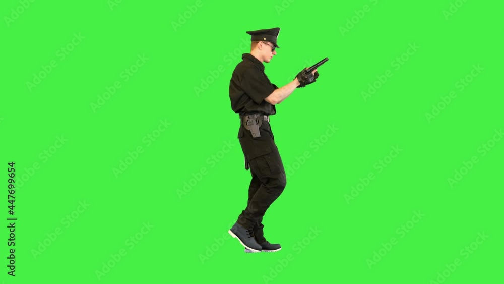 Policeman walks doing some exercices with his gun on a Green Screen ...