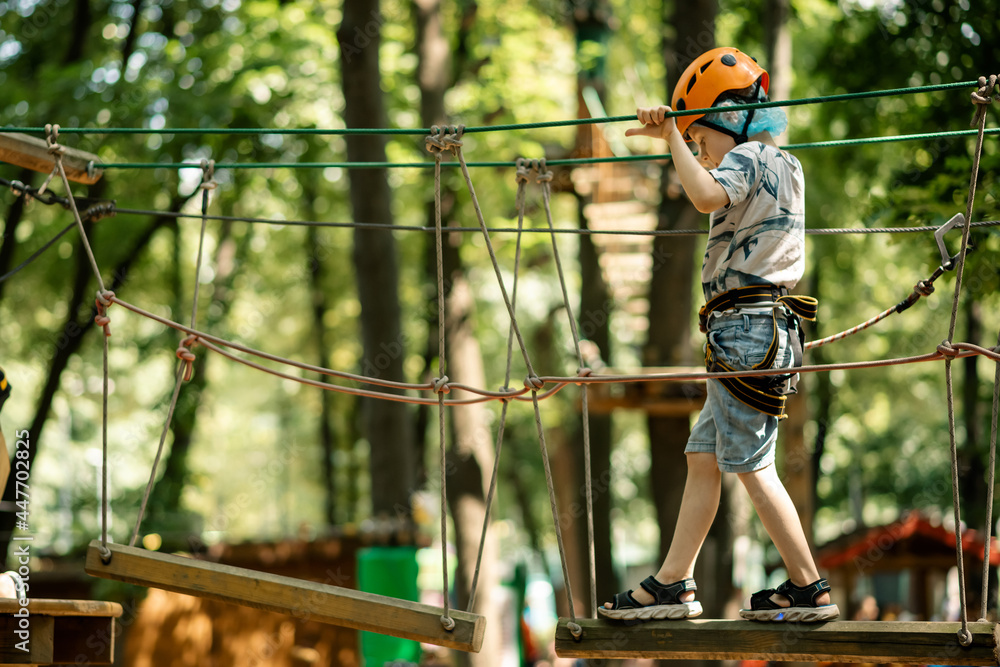 Rope park for children. A young boy in a flap climbs obstacles. Active ...