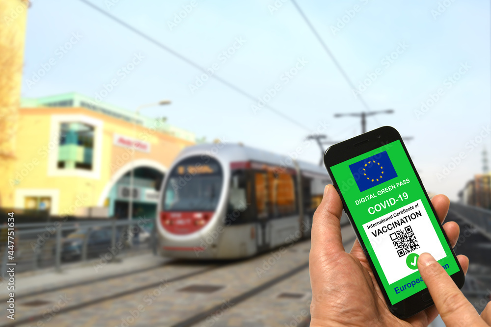 A man at a tram stop holds a smartphone with the European Union digital ...