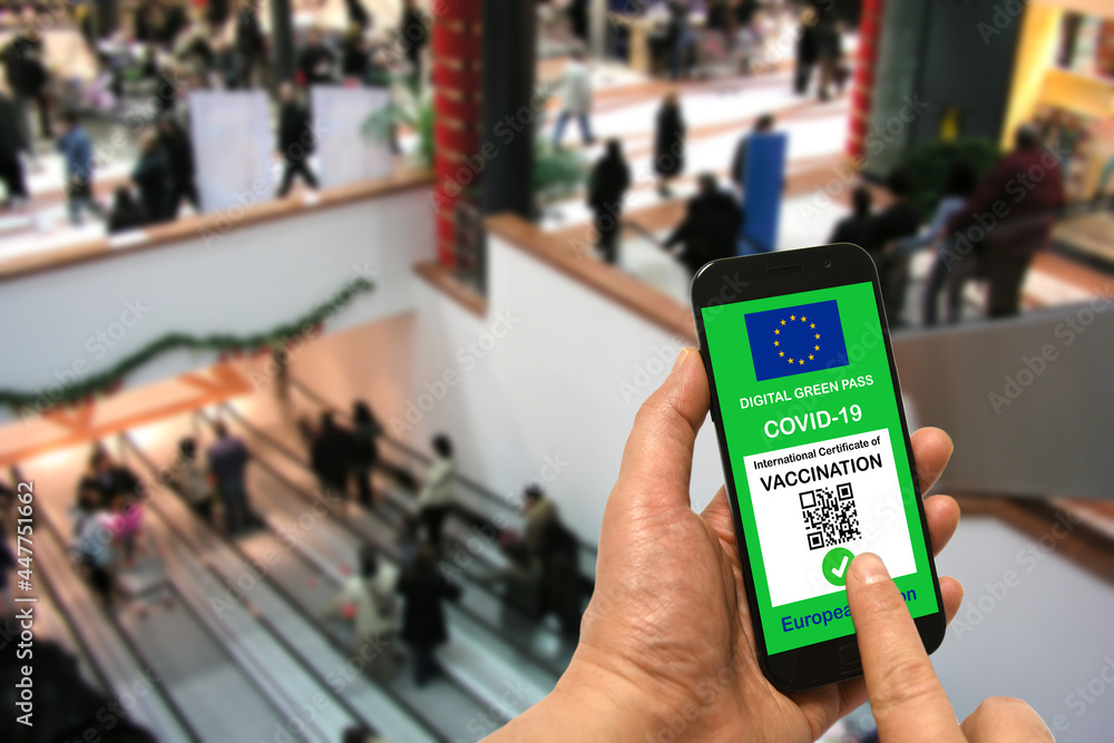 A man in a shopping mall holds a smartphone with the European Union ...