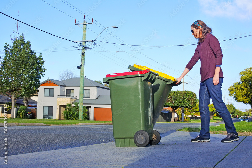 Woman puts recycling bins outside her home on waste collection day ...