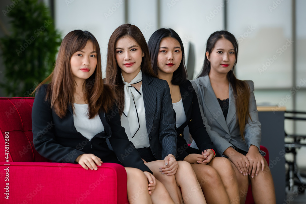 Group of four attractive Asian female office colleagues in formal ...