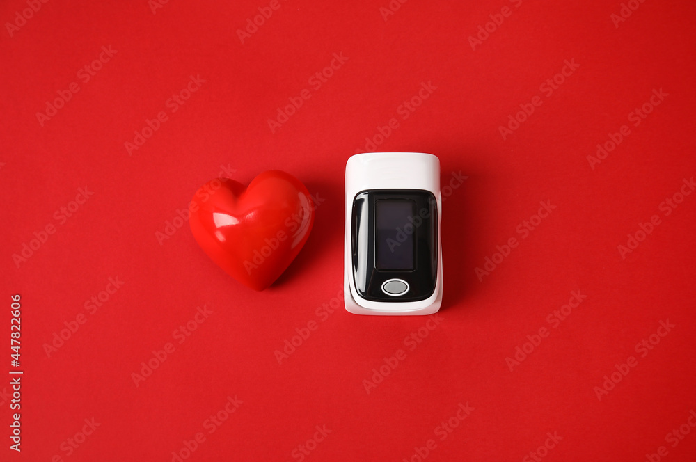 Pulse oximeter and red heart on color background Stock Photo | Adobe Stock