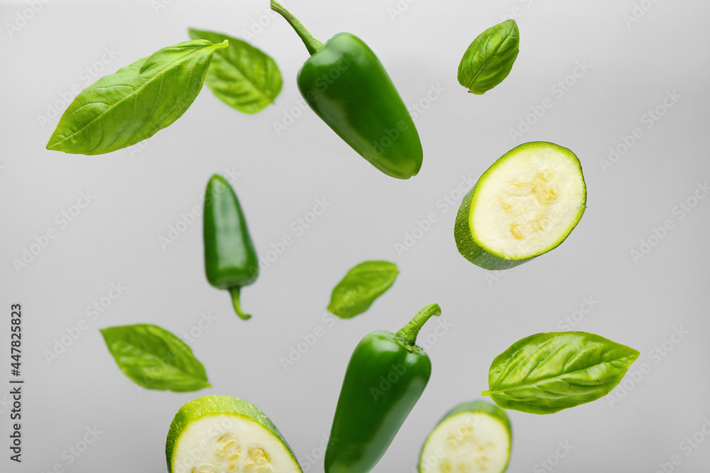 Flying green vegetables on light background Stock Photo | Adobe Stock