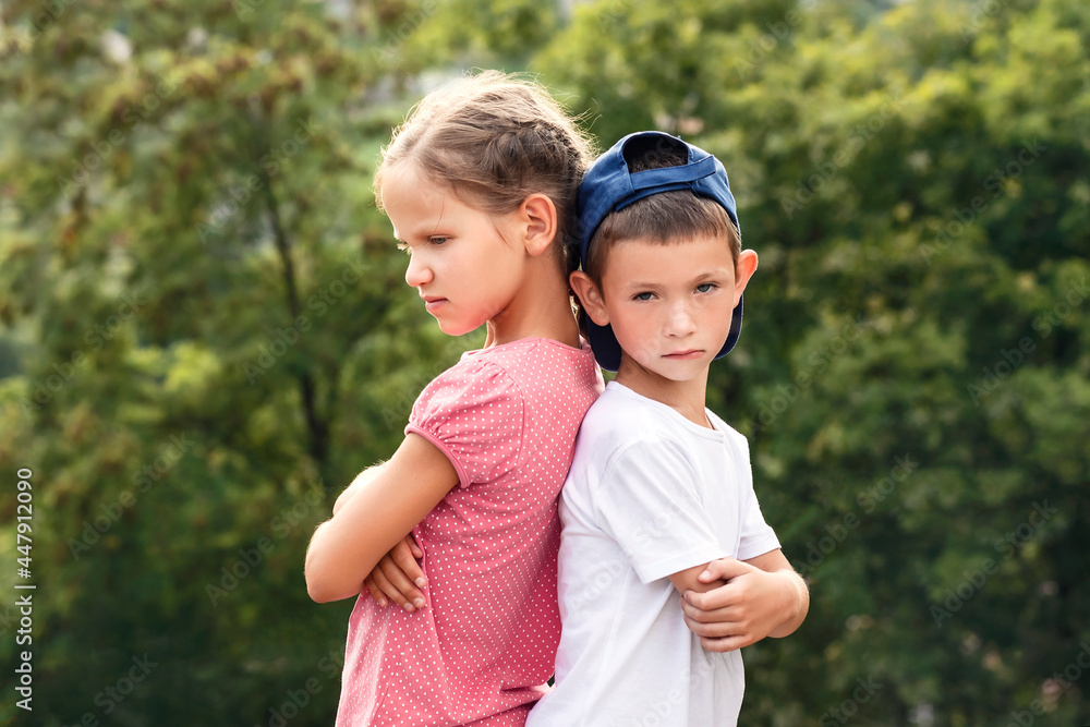 Little boy and girl stand with their backs to each other. Sad offended ...