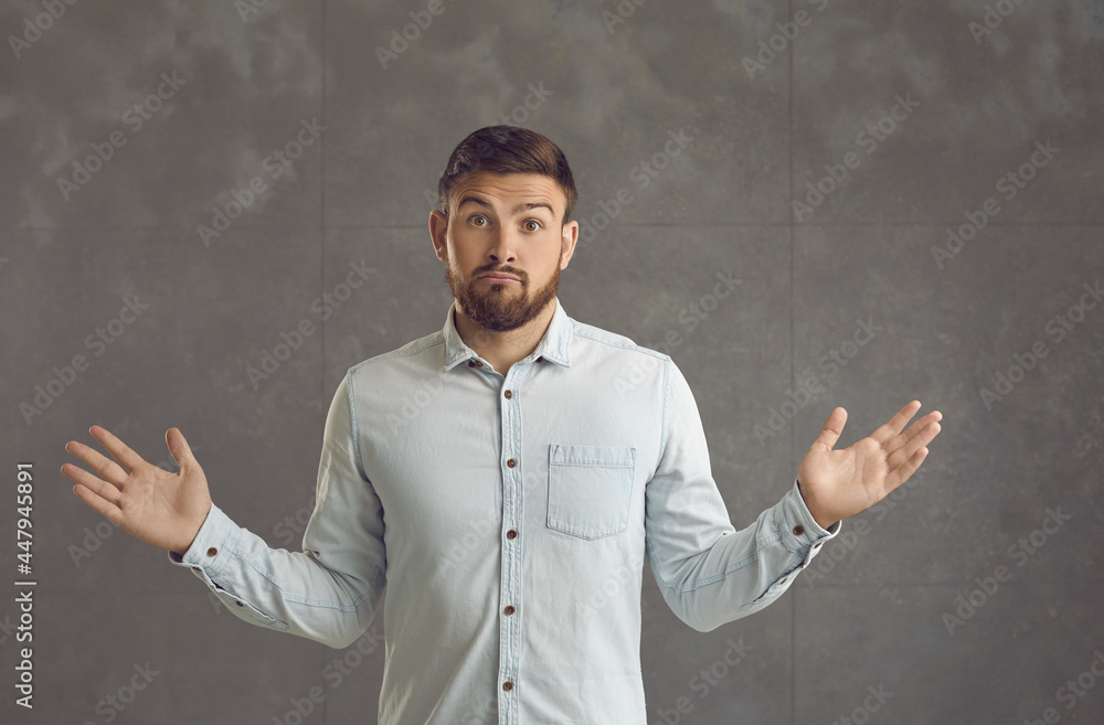 Portrait of a handsome young man standing on a grey studio background ...
