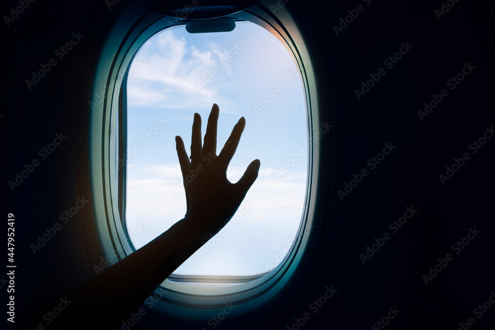 The hand of the woman wearing the ring was touching the plane window ...