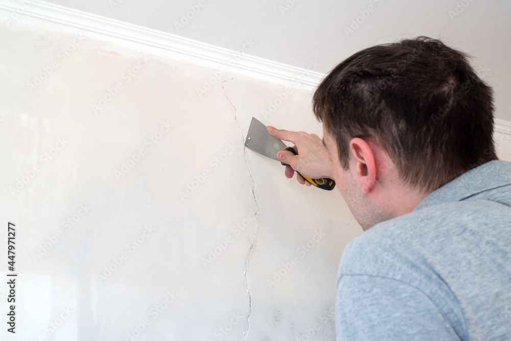 Construction man worker repairing a crack wall of a home, plastering ...