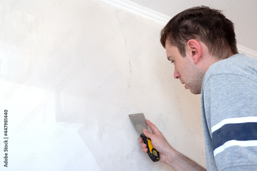 Construction man worker repairing a crack wall of a home, plastering ...