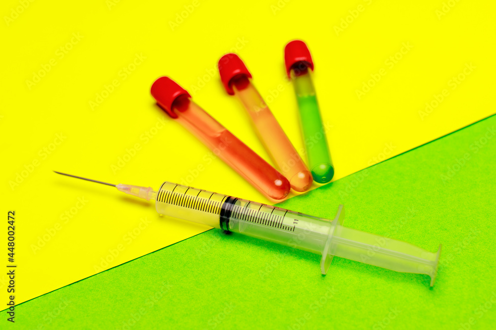 Medical syringe with needle and sample tes tubes on colorful background ...