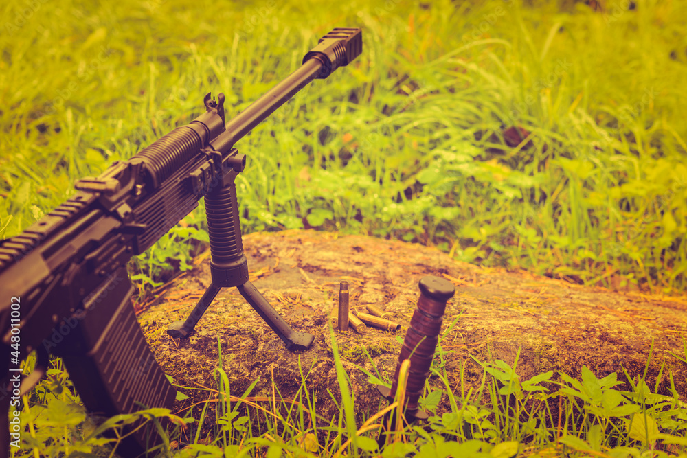 Rifle standing on a bipod with empty shells on the rock and combat ...