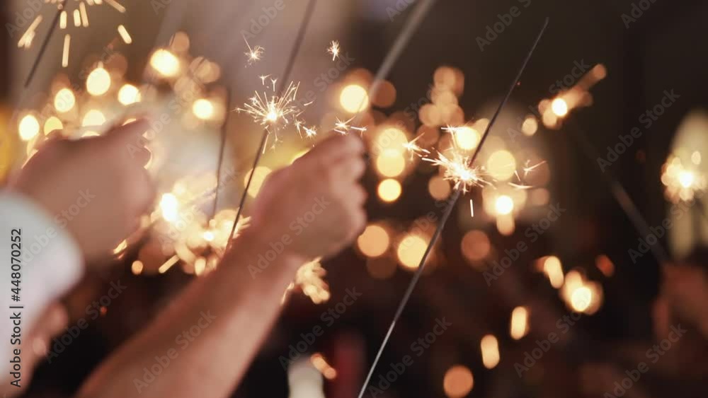 Close up hands holding sparklers group of friends celebrating waving ...