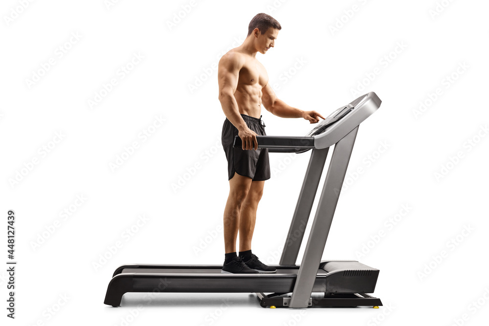 Full length profile shot of a shirtless young man setting a program on ...