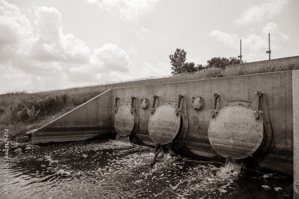 Heavy metal flood control gate discharging into a waterbody Stock Photo ...