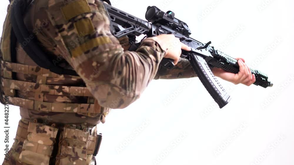 Man in combat camouflage and body armor takes aim with his assault ...