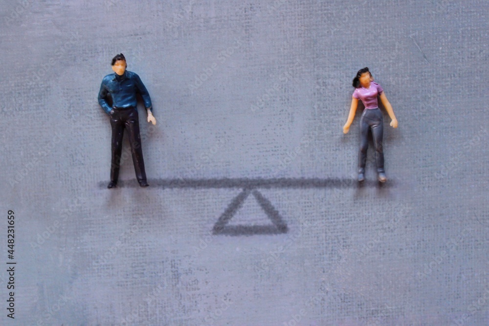 Gender equality concept. Miniature man and woman standing on balance ...