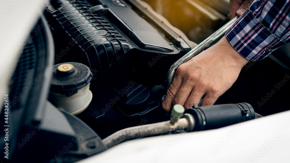 A young man checking and maintaining the engine of his car. Open the ...