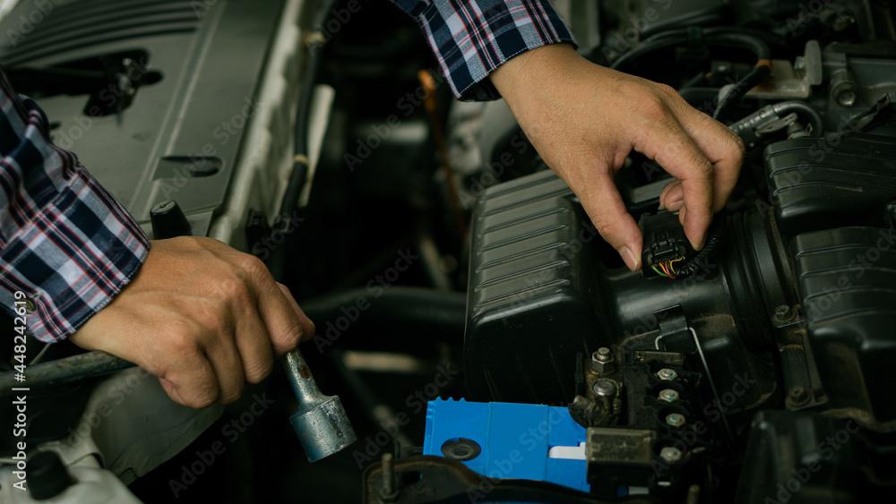 A young man checking and maintaining the engine of his car. Open the ...