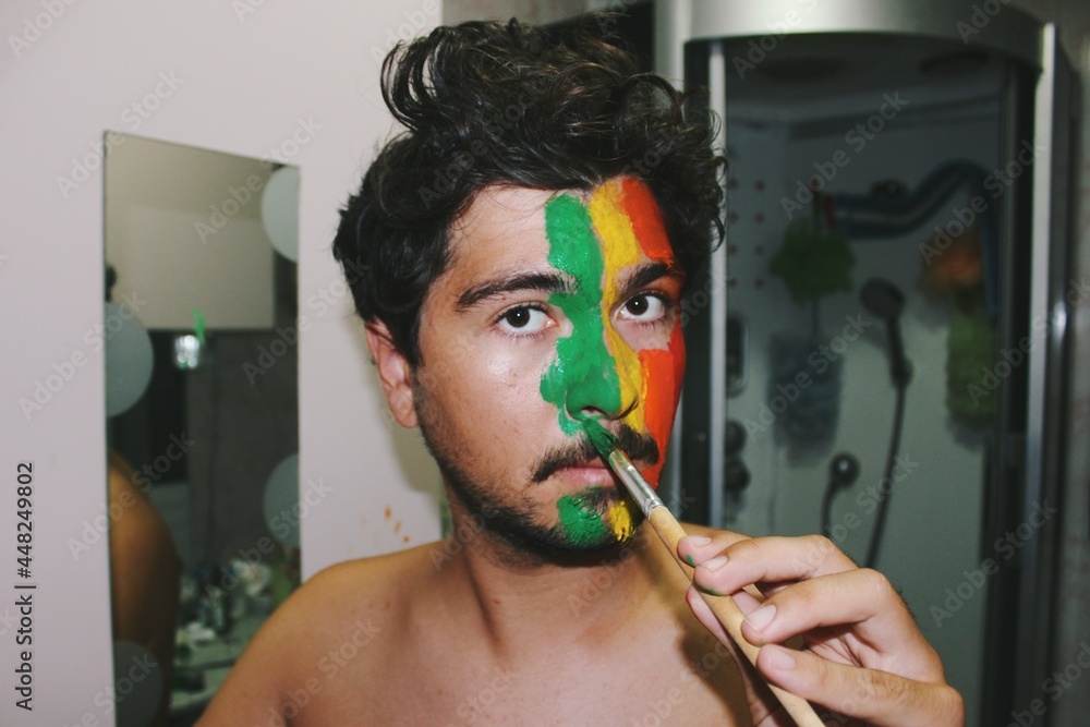 Funny portrait of young man while drawing lgbtq rainbow pride flag into ...